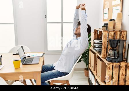Young hispanic businessman relaxed stretching arms at the office Stock ...