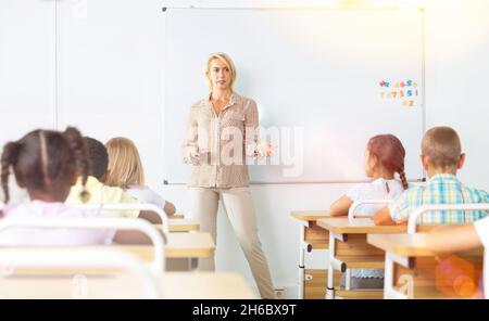 Woman teacher is giving interesting lecture for primary school students ...