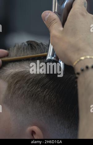 Vertical shot of a barber's hands cutting a client's hair with scissors ...