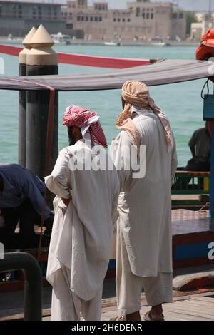 Arab men in traditional dress amid sand dunes of Liwa, Abu Dhabi, UAE ...