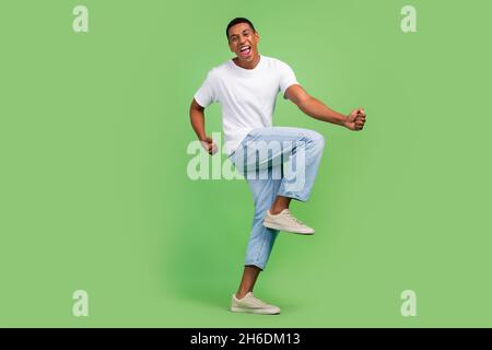 Photo of funky lucky young guy wear green sweater playing modern gadget ...