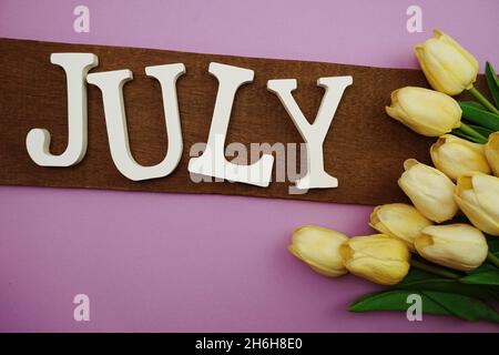 July alphabet letter and tulip flower with space copy on purple ...