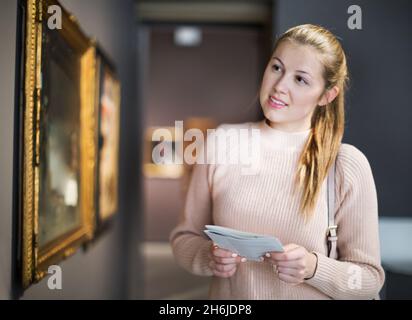Woman with guide looking at pictures in museum Stock Photo - Alamy