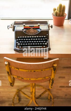 Black, wooden chair and desk with a typewriter set on green wall with ...