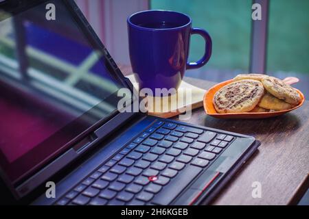 Notebook beside pastries, pen, and a cup of coffee on a wooden table ...
