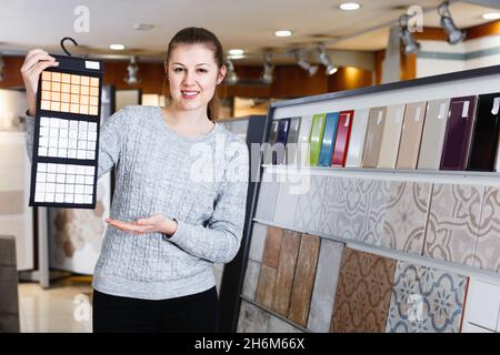 Portrait of female looking sample of ceramic tile in shop Stock Photo ...