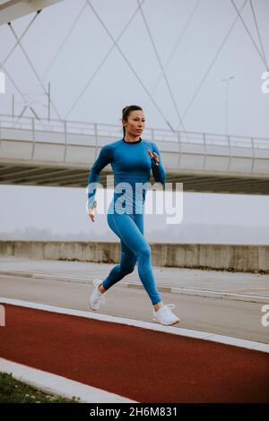 Young woman in blue track suit running toward camera on the forest ...