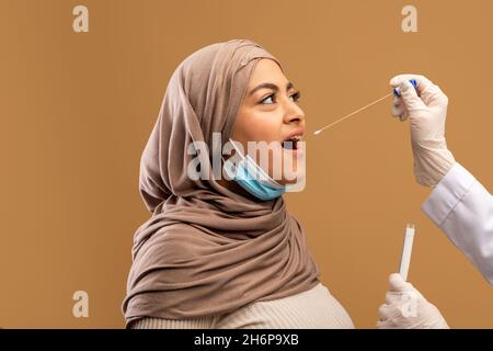 Muslim woman getting PCR oral coronavirus swab test, female doctor ...