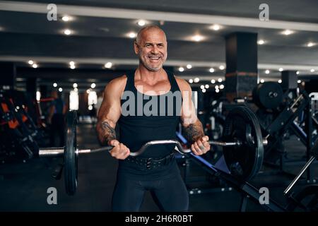 Bald bodybuilder doing chest exercise on cross machine in gym Stock ...
