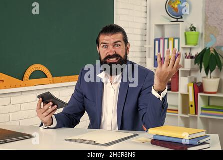 confused man with beard calculating on calculator in school math lesson ...