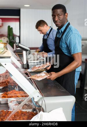 Successful owner of butcher store preparing fresh meat products for ...