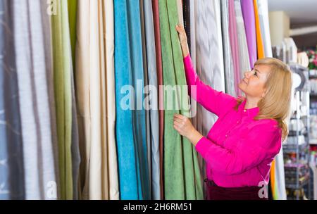 Mature female choosing curtains in the curtains shop Stock Photo - Alamy
