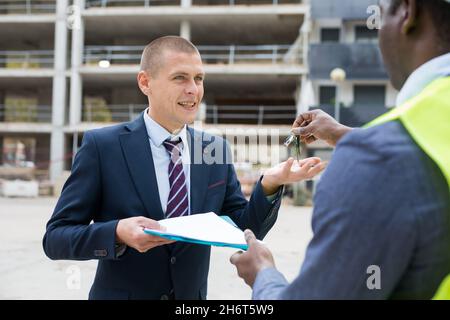 African-american contractor hands the keys to a man customer Stock ...