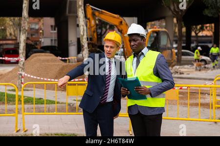 Engineer and architect are discussing options for laying a pipe on ...