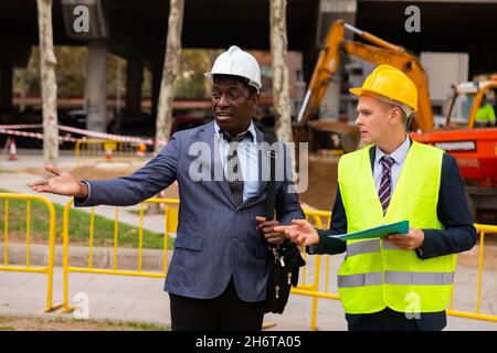 African-american foreman works shows something to a man worker Stock ...