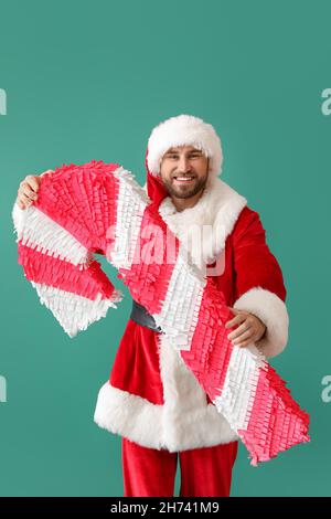 Santa Claus with candy cane pinata sitting on green background Stock ...