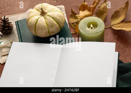 Opened book with blank pages, pumpkin and autumn leaves on dark ...