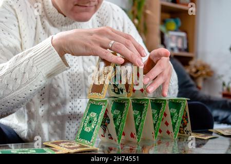 Hands of a woman stacking a tower from playing cards. Close up ...