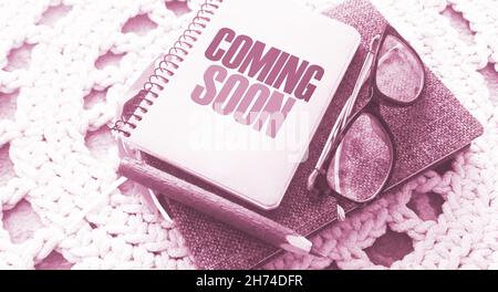 Coming soon on the cover of copybook, glasses and pen on crochet carpet ...