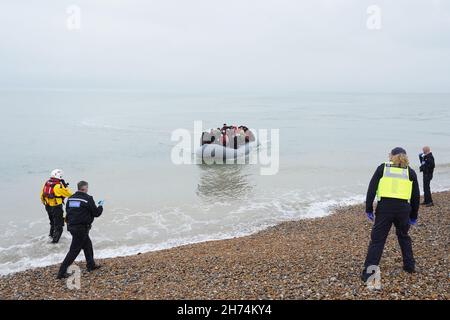 Police watch people thought to be migrants boarding a small boat in ...