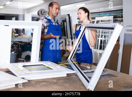 Foreman explaining plastic windows assembly process to young female ...