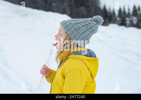 cute little girl while eating icicle on beautiful winter day Stock ...