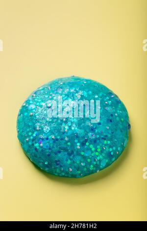 blob of blue slime with glitter on yellow background Stock Photo - Alamy