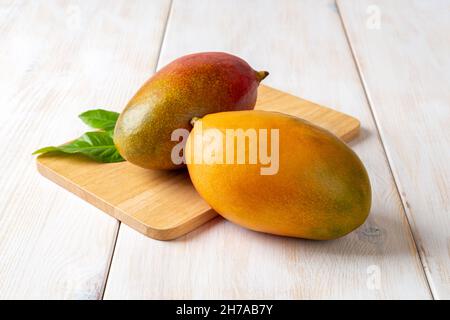 Whole ripe yellow Palmer mango on the turquoise plate over bright ...