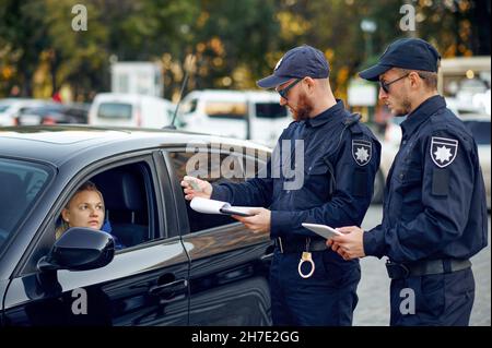 Police officers checking driving license of male driver violated speed ...