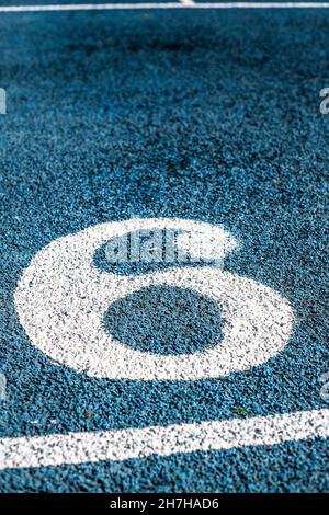 Number six. White athletic track number on red rubber racetrack ...