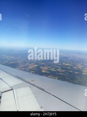 Airplane wing and land far under the plane. Flight in the deep blue sky ...