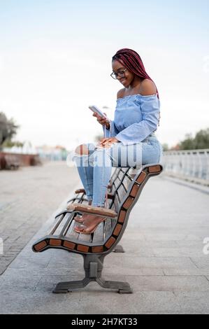 Smiling woman with braided hair using smart phone Stock Photo - Alamy
