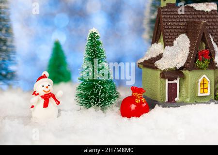toy snowman with a bag of gifts near a small house, christmas greeting ...