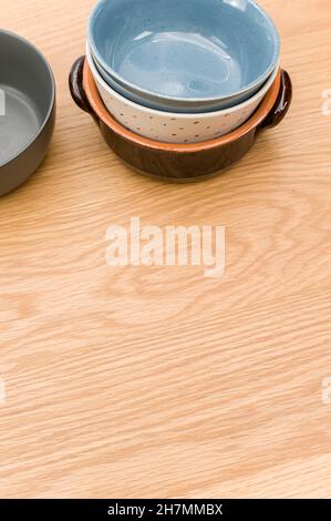 colorful piled up empty stoneware bowls on a wooden tabletop with copy ...