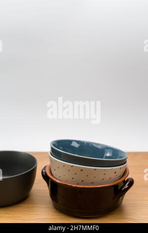 colorful piled up empty stoneware bowls on a wooden tabletop with copy ...