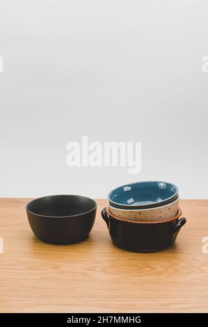 colorful piled up empty stoneware bowls on a wooden tabletop with copy ...