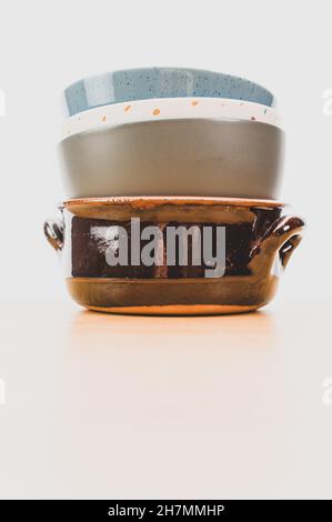 colorful piled up empty stoneware bowls on a wooden tabletop with copy ...