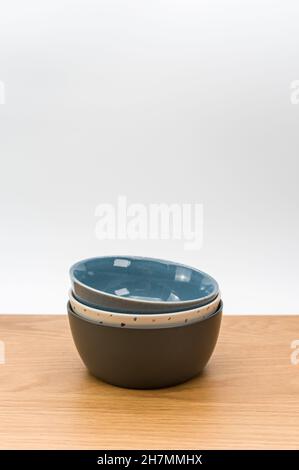 colorful piled up empty stoneware bowls on a wooden tabletop with copy ...