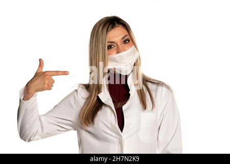 Young beautifuls female doctor pointing on her face medical mask on a ...