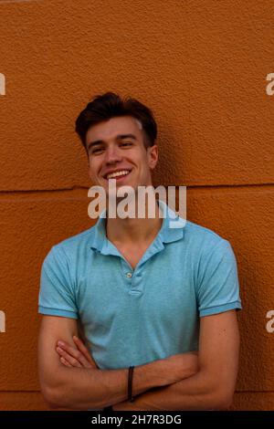 Handsome stylish Spanish man leaning on a red wall and posing with a ...