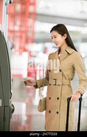 Businesswoman using ticket machine at the airport Stock Photo - Alamy