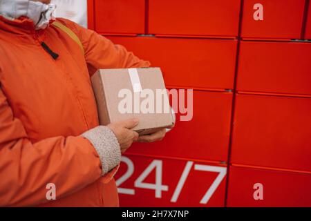 Woman picks up mail from automated self-service post terminal machine ...