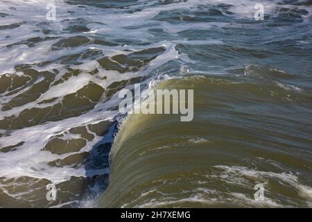 A single wave cresting during high tide and rough surf on the northeast ...