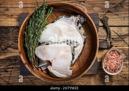 Raw wolffish or wolf fish fillet in a wooden plate. Isolated, white ...
