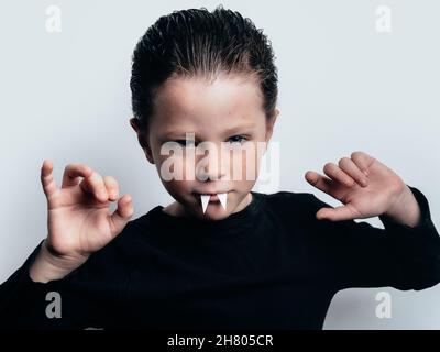 Spooky boy with white fangs looking at camera with frightening ...