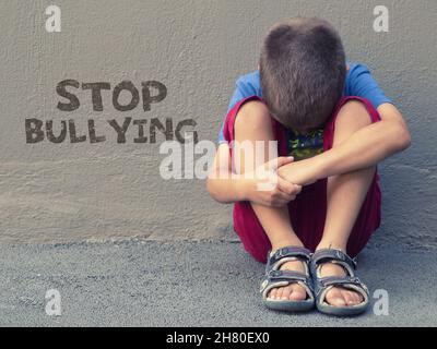 People bullying sad little boy near white wall Stock Photo - Alamy