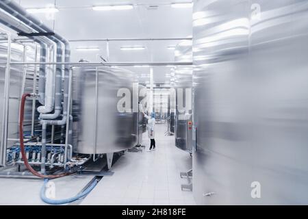 Female chemical plant process operator walkway to storage tank pipes ...
