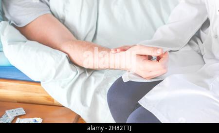 The doctor examines the patient's pulse by hand and records the results ...