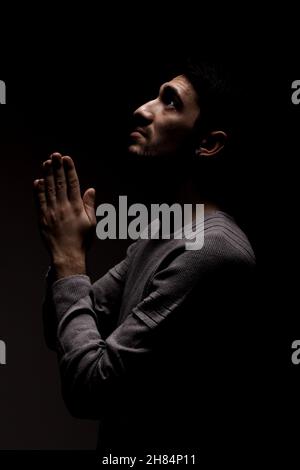 Young man praying in darkness Stock Photo - Alamy