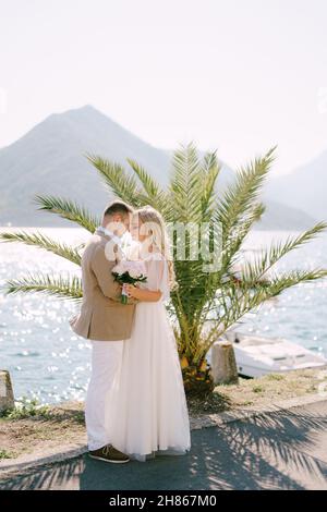 Groom and bride stand on the embankment, leaning on the handrail Stock ...